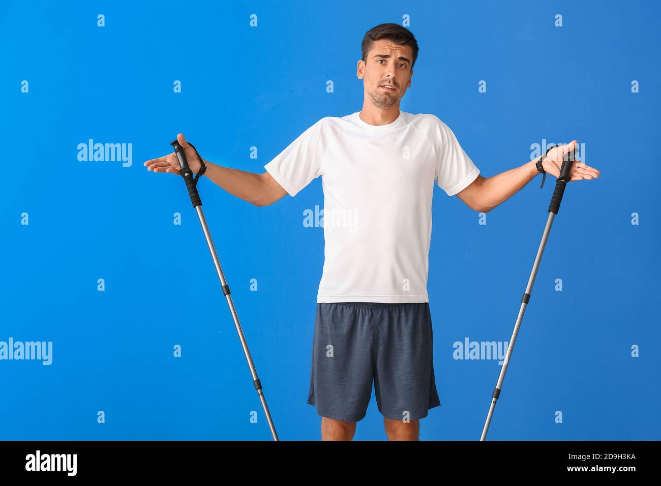 Confused young man with walking poles on color background Stock Photo ...