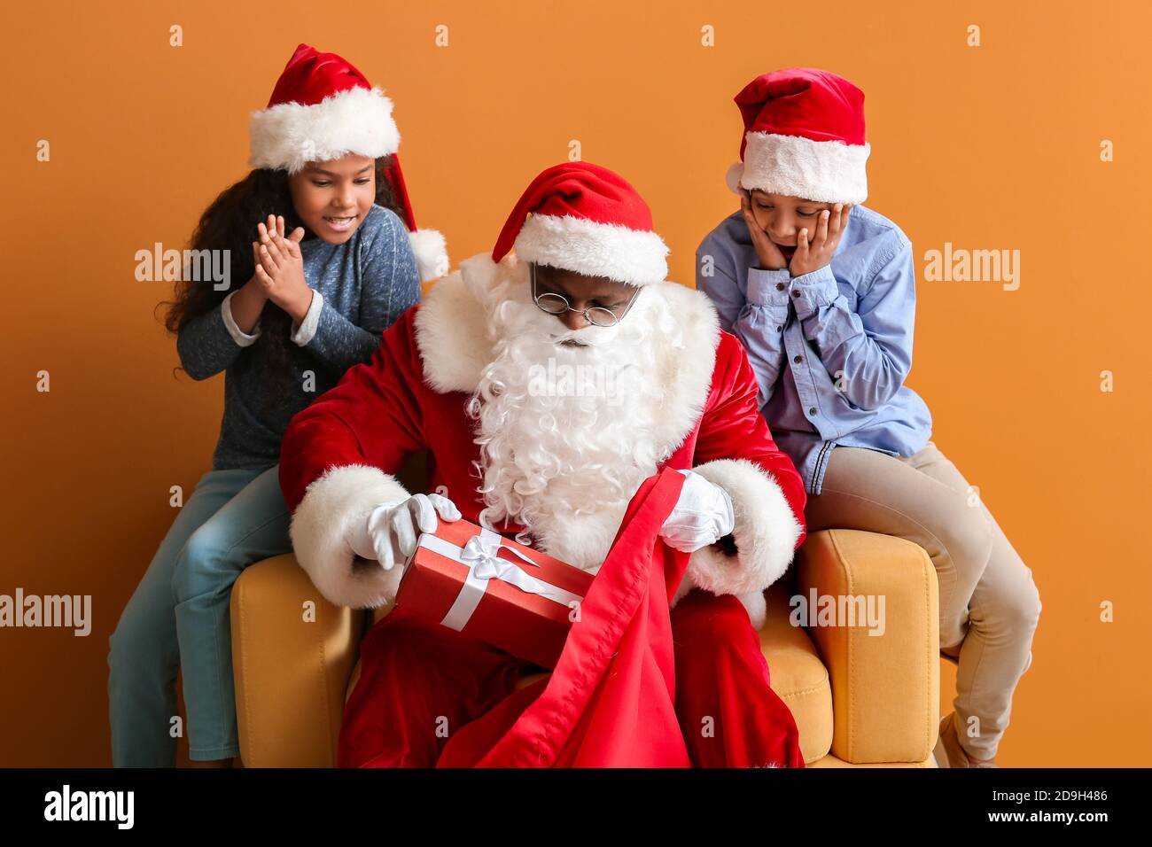 African-American Santa Claus taking gifts for cute children from his ...