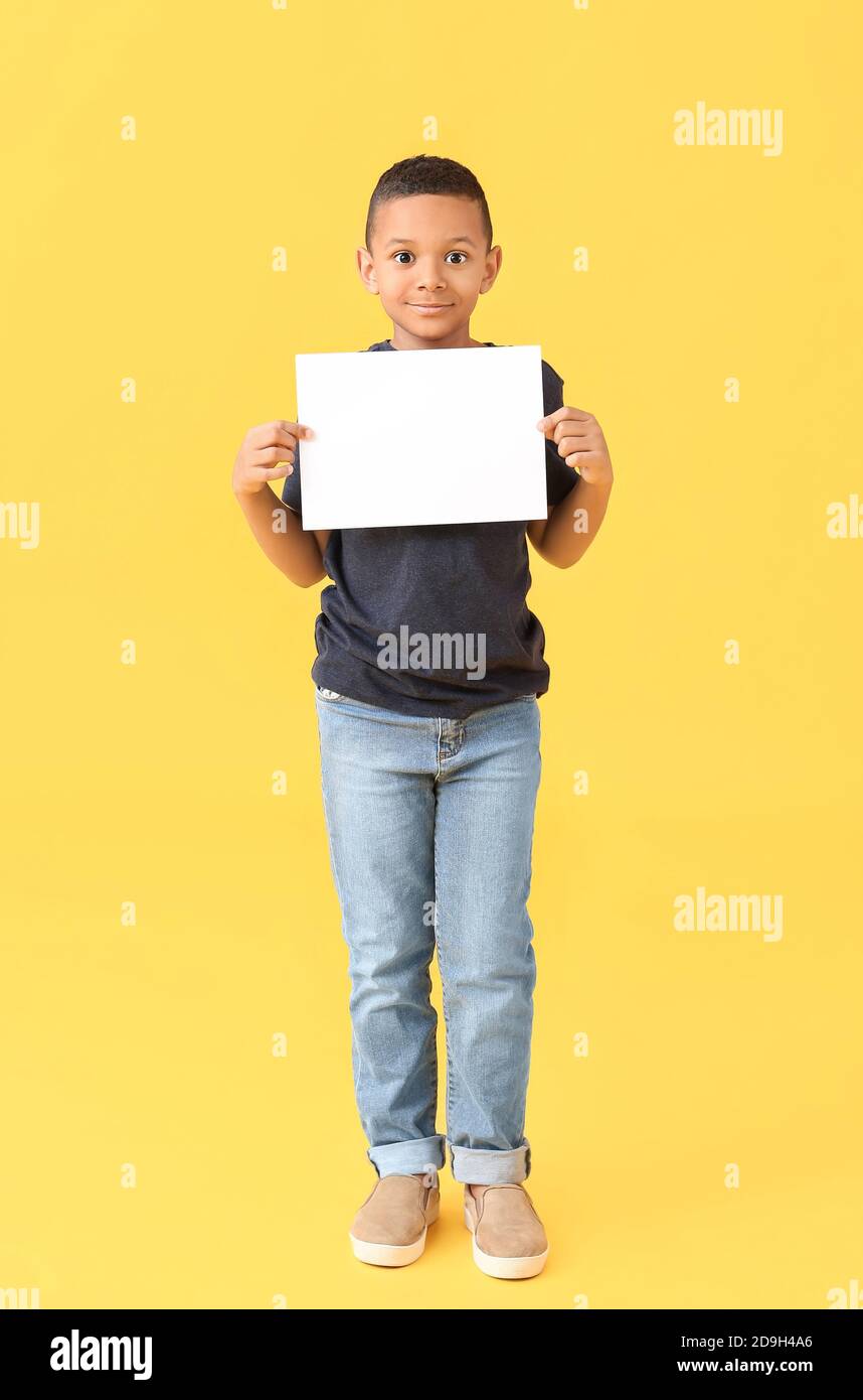 Little African-American boy with blank paper sheet on color background ...