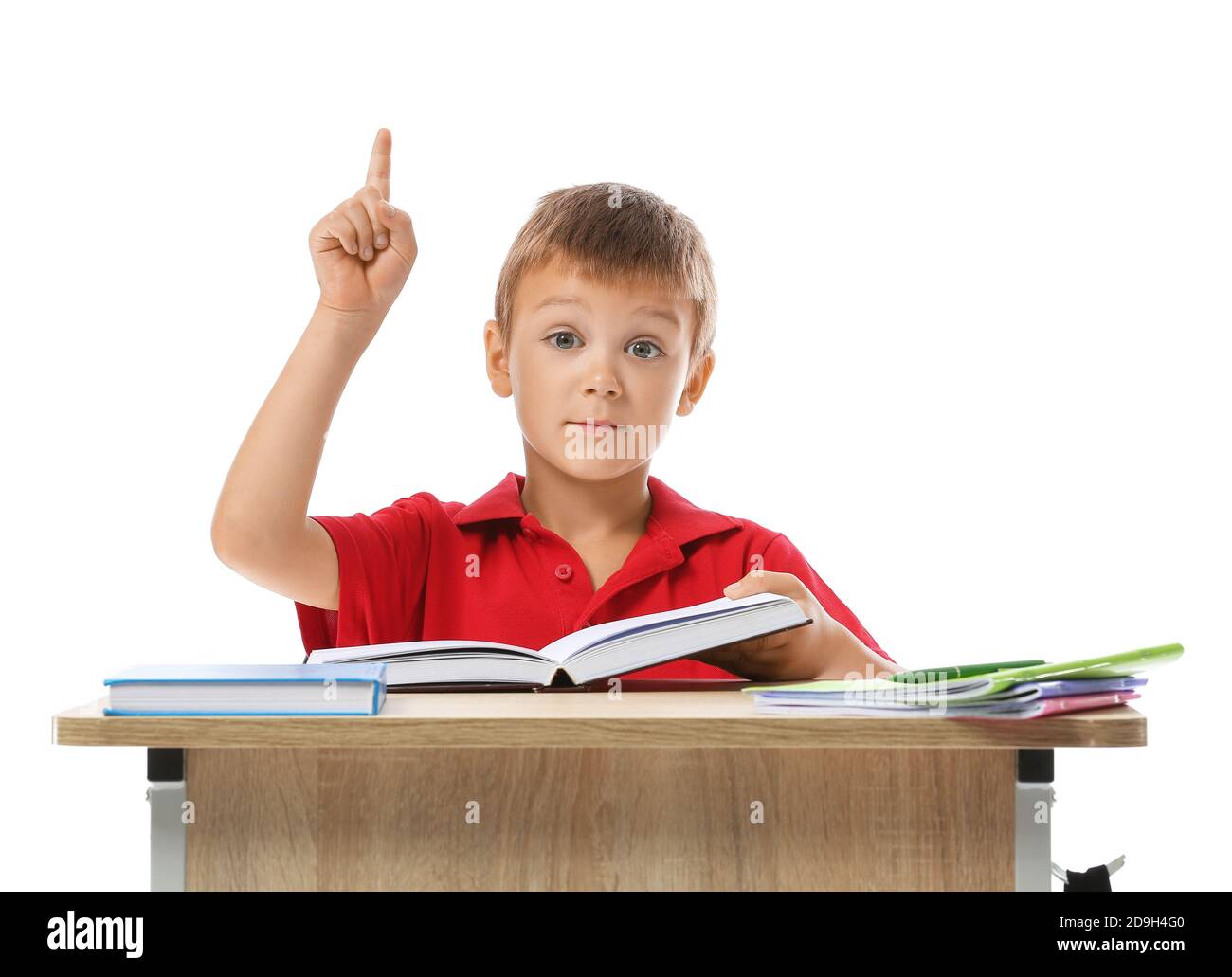 Little pupil with raised index finger sitting at school desk against ...