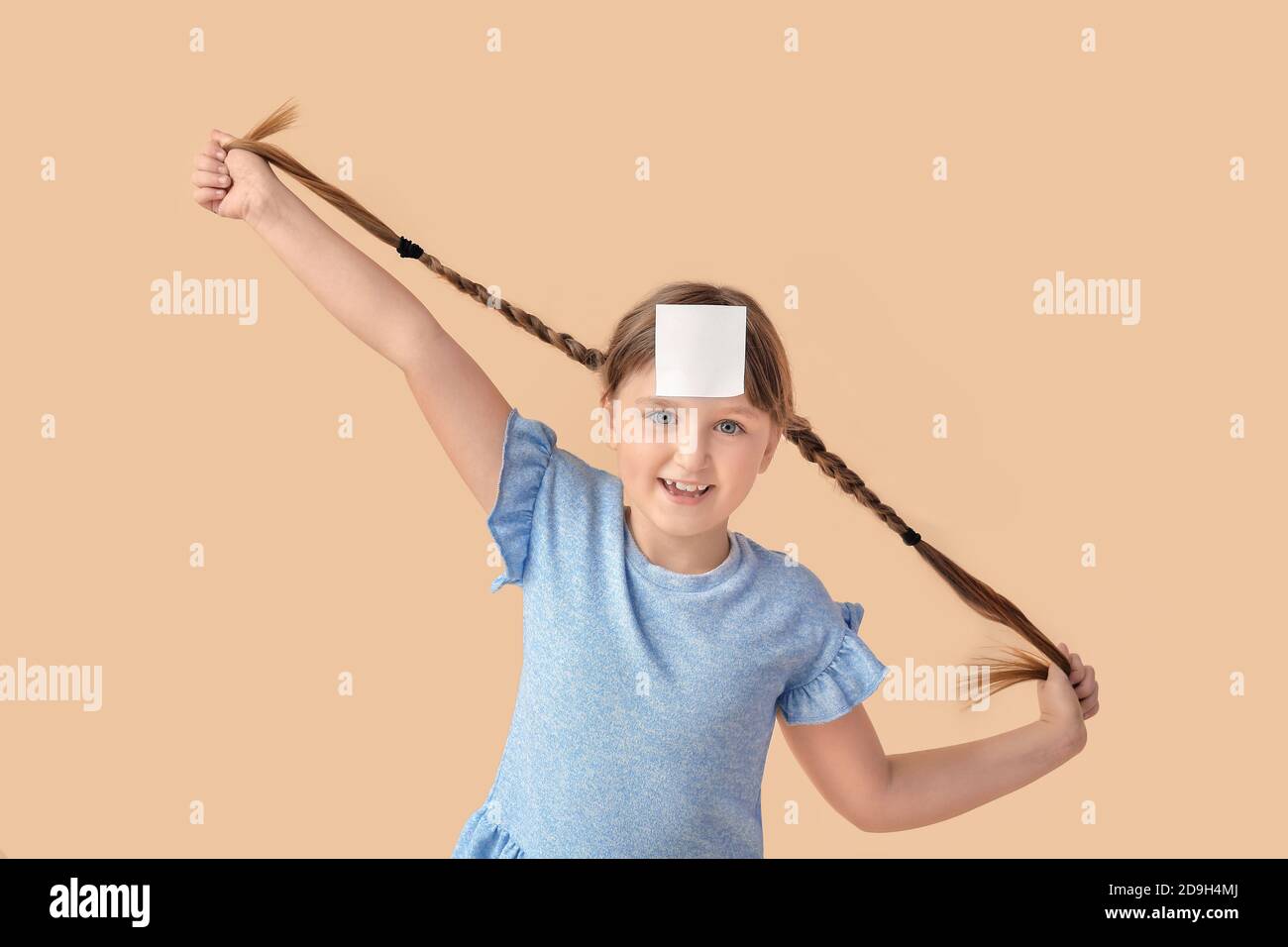 Little girl with blank note paper on her forehead against color ...
