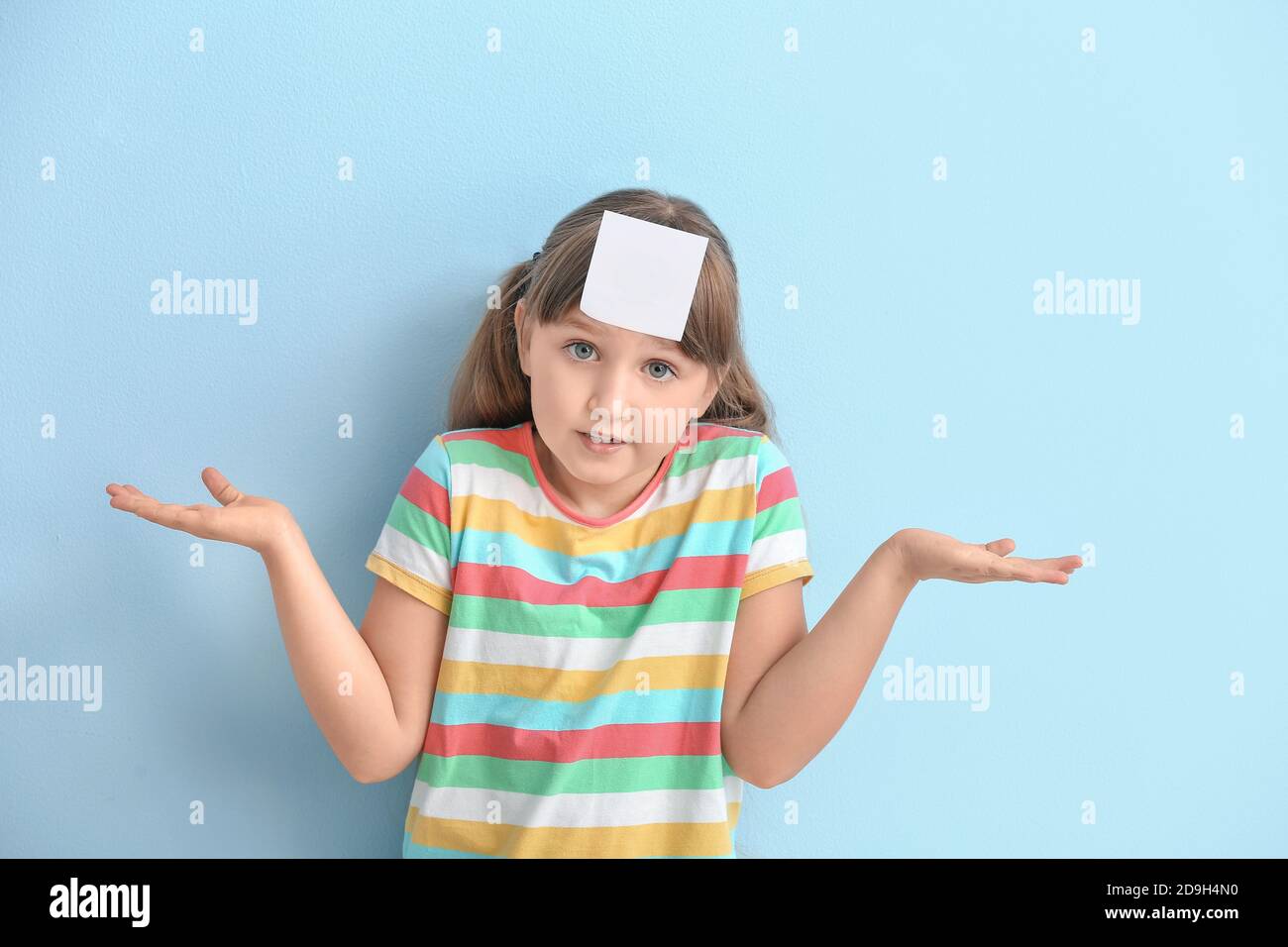 Little girl with blank note paper on her forehead against color ...