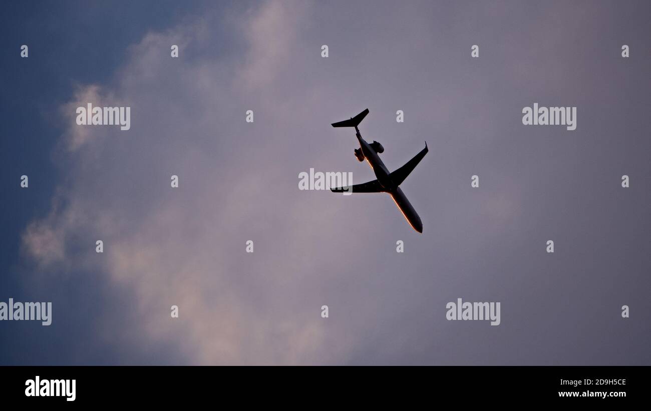Aircraft flying west in the dusk of a cloudy day Stock Photo - Alamy