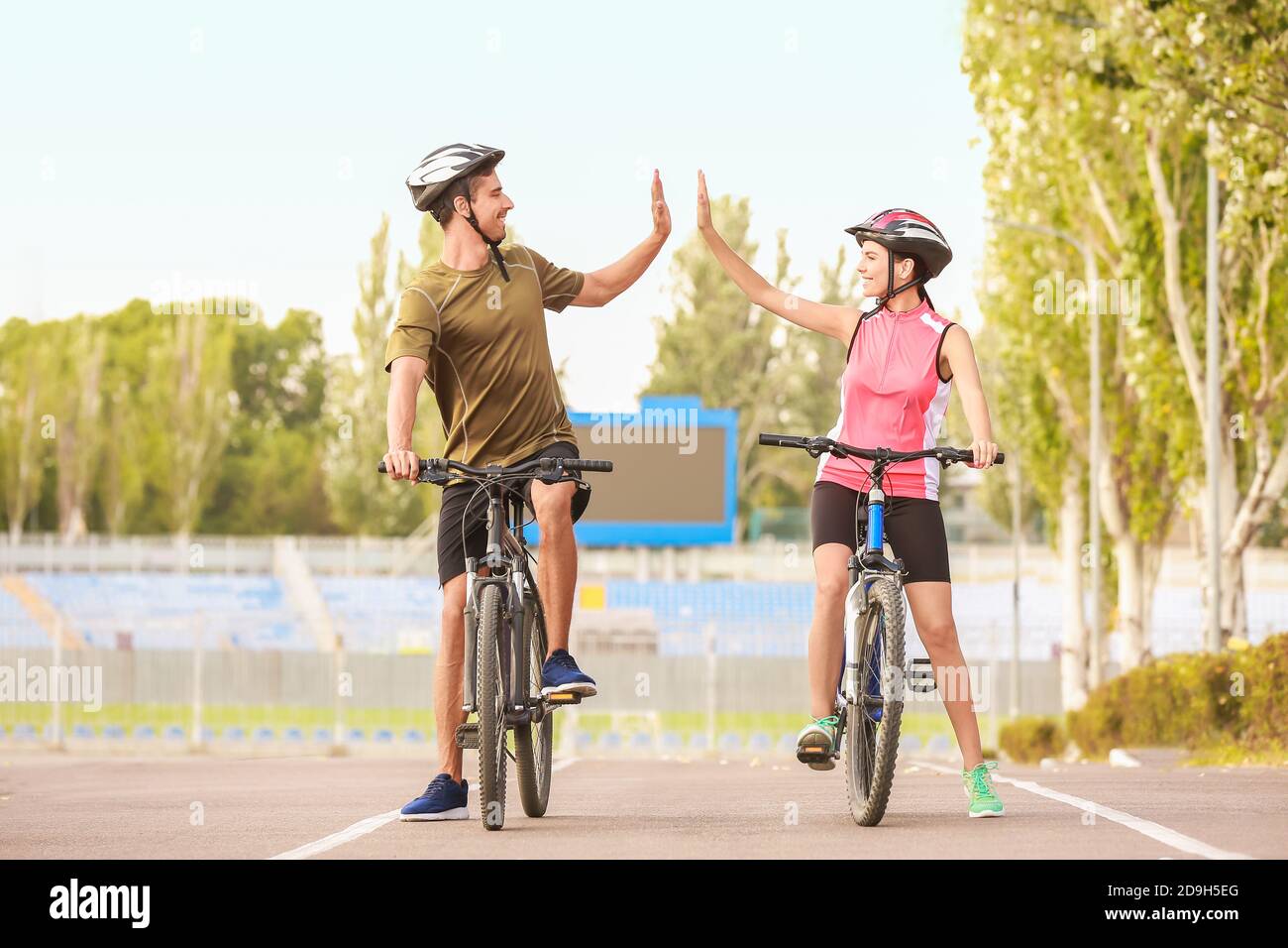 Male and female cyclists giving each other high-five outdoors Stock ...