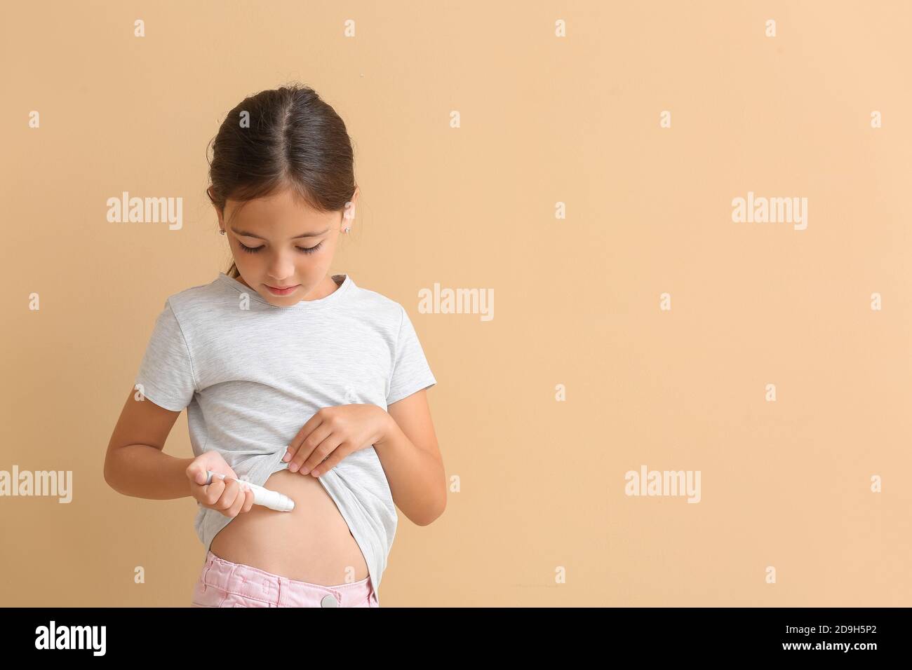 Little diabetic girl giving herself insulin injection on color ...