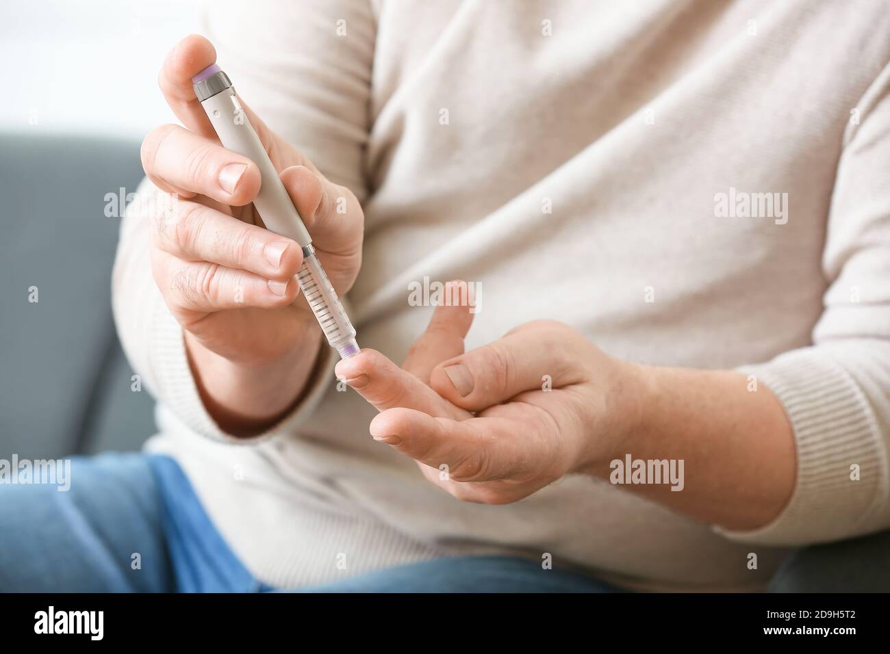 Senior diabetic man taking blood sample with lancet pen at home Stock ...