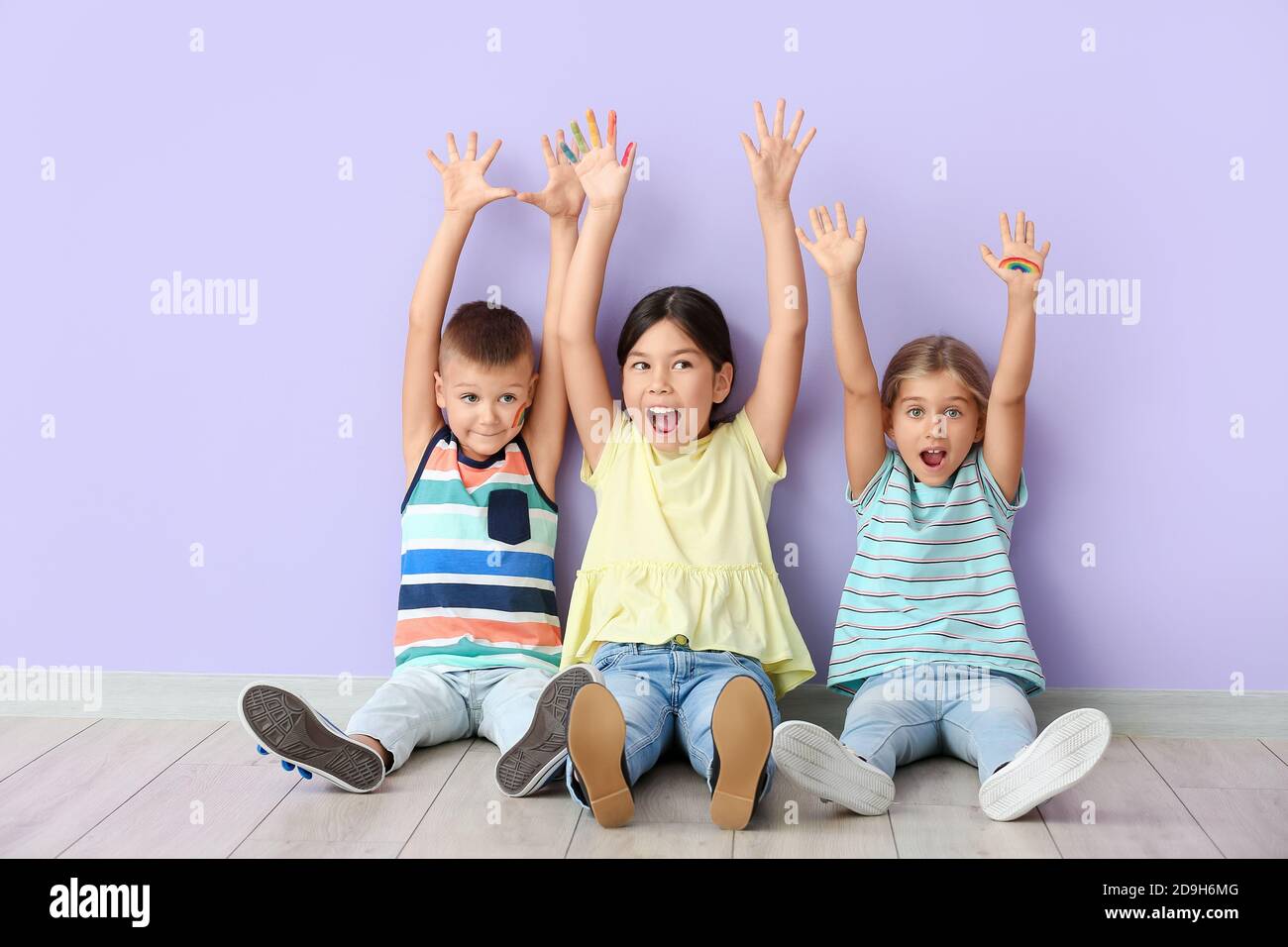 Happy little children sitting near color wall Stock Photo - Alamy