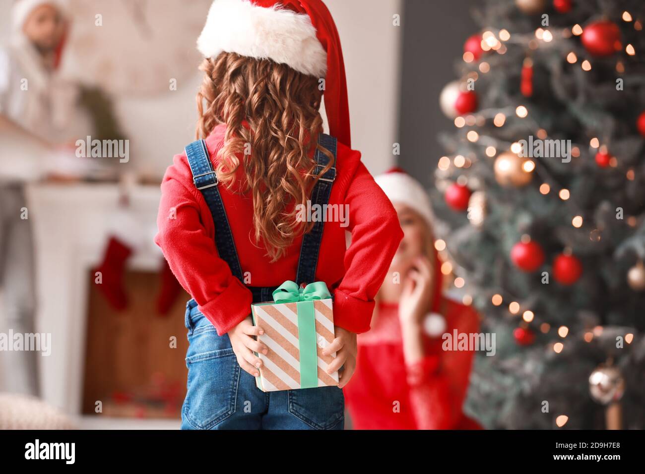 Cute girl hiding gift for her parents on Christmas eve Stock Photo - Alamy