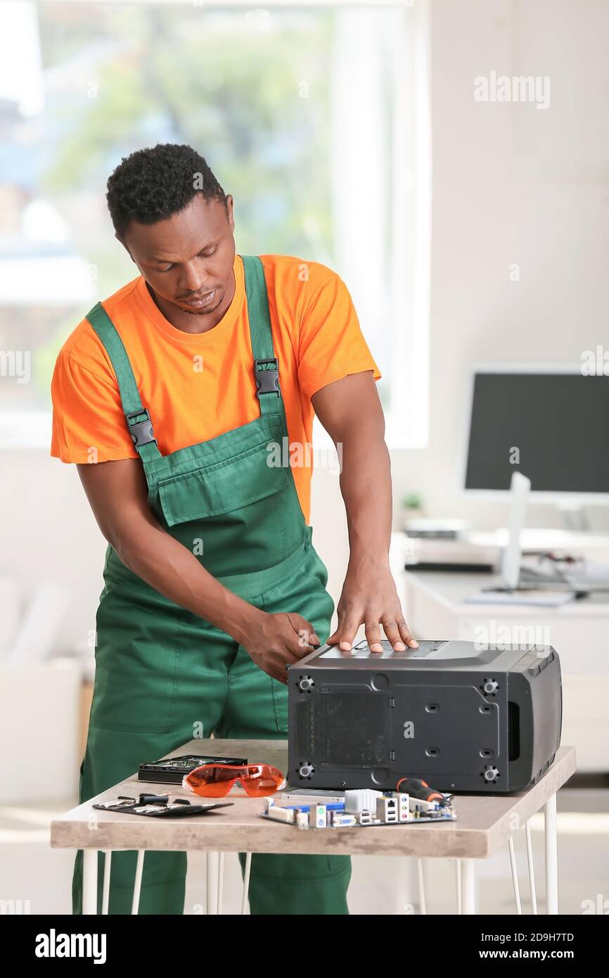 African-American technician repairing computer in service center Stock ...