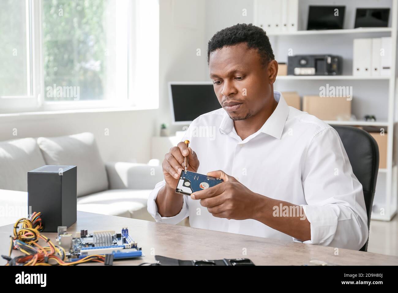 African-American technician repairing computer in service center Stock ...
