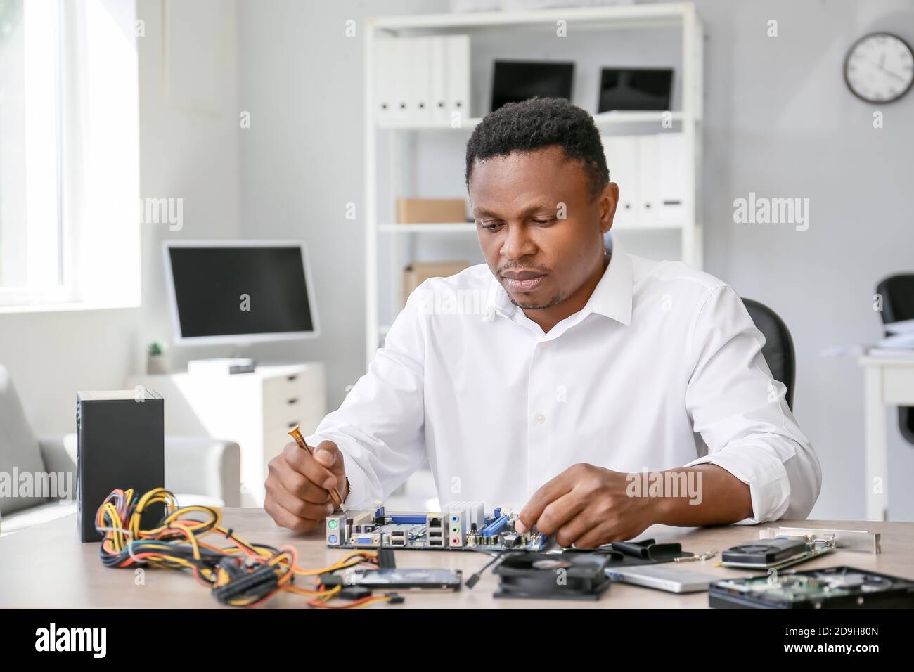 African-American technician repairing computer in service center Stock ...