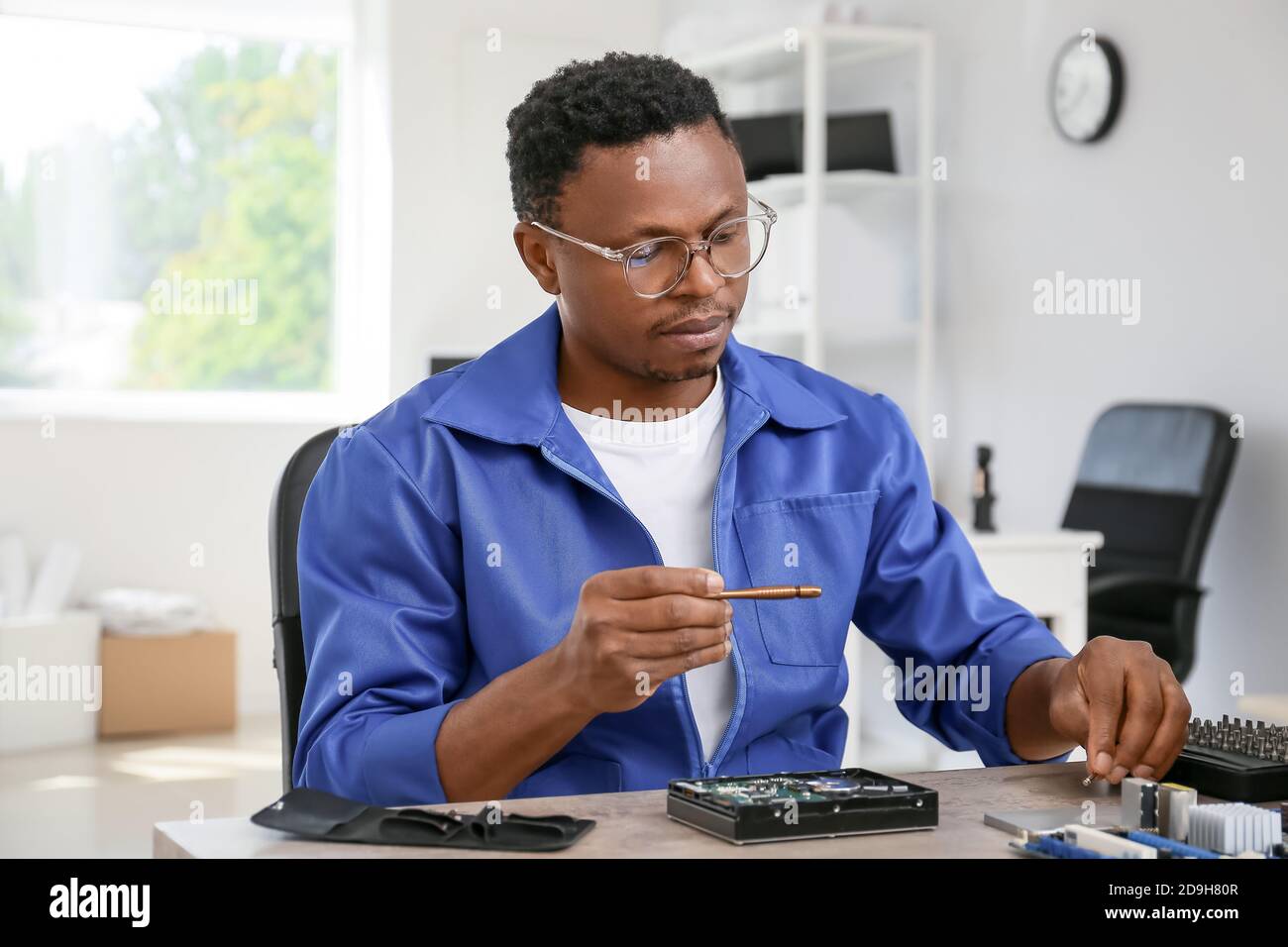 African-American technician repairing computer in service center Stock ...