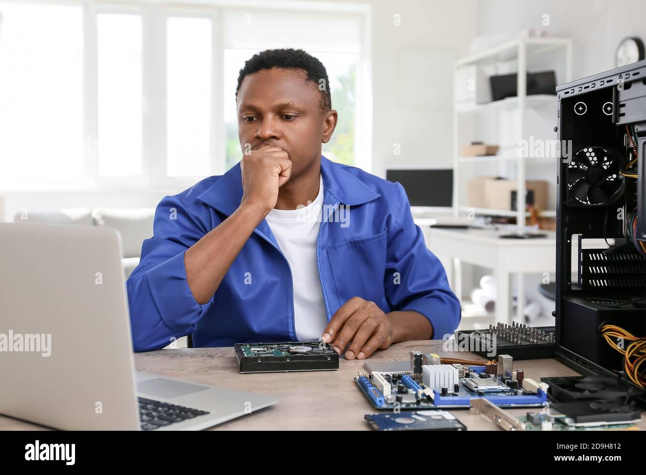 African-American technician repairing computer in service center Stock ...