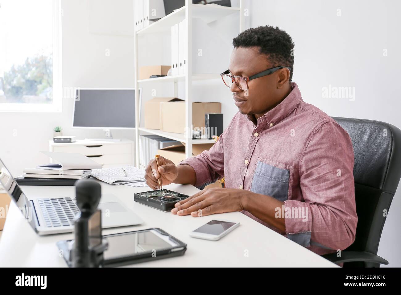 African-American technician repairing computer in service center Stock ...