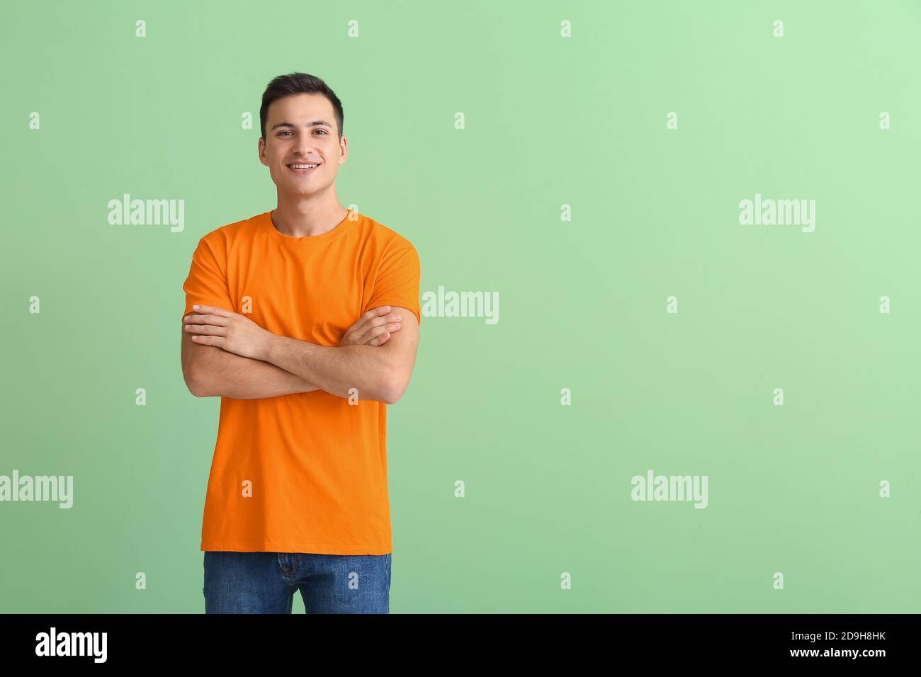 Handsome young man in orange t-shirt on color background Stock Photo ...
