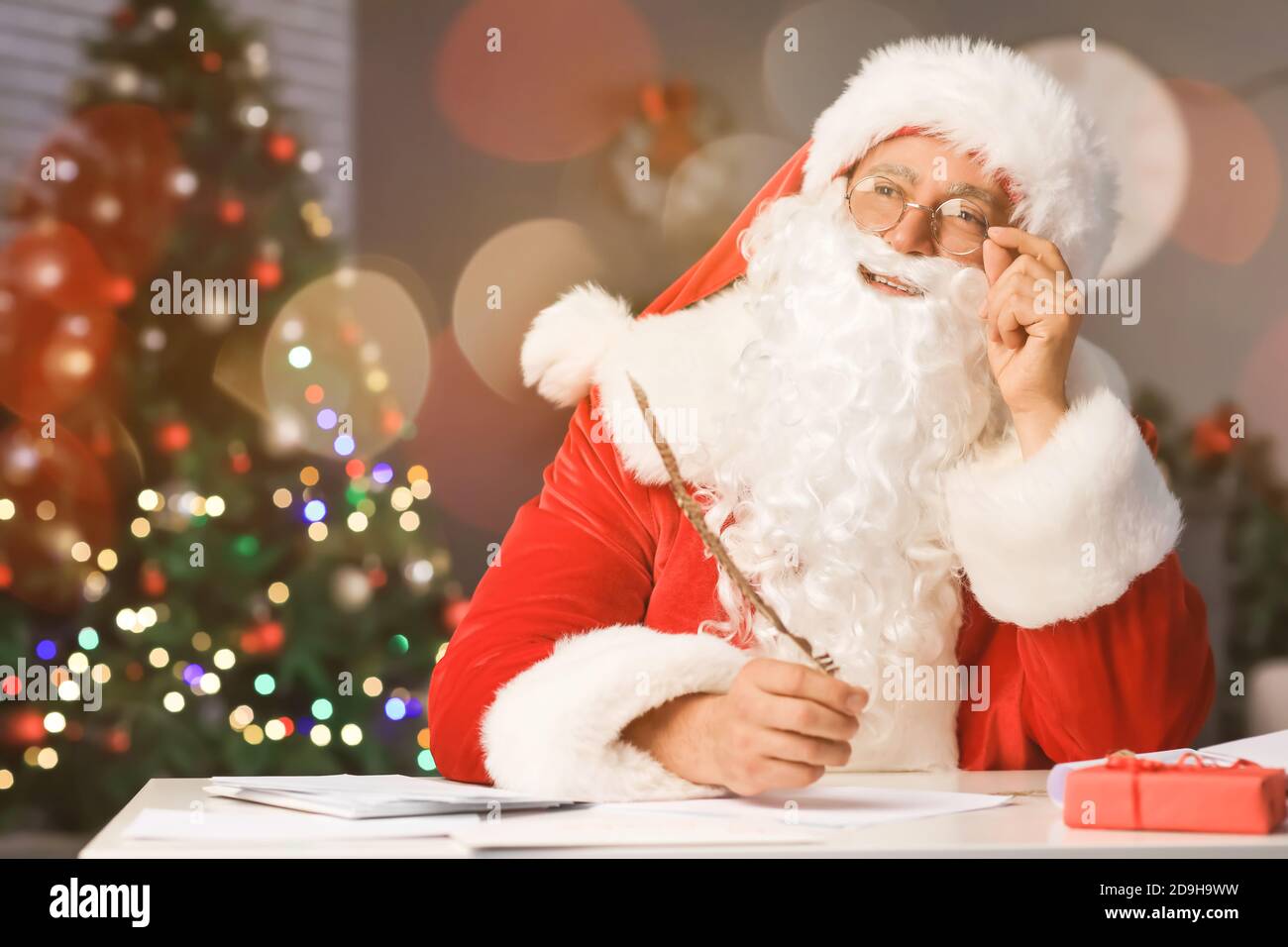 Santa Claus making list of gifts at table Stock Photo - Alamy