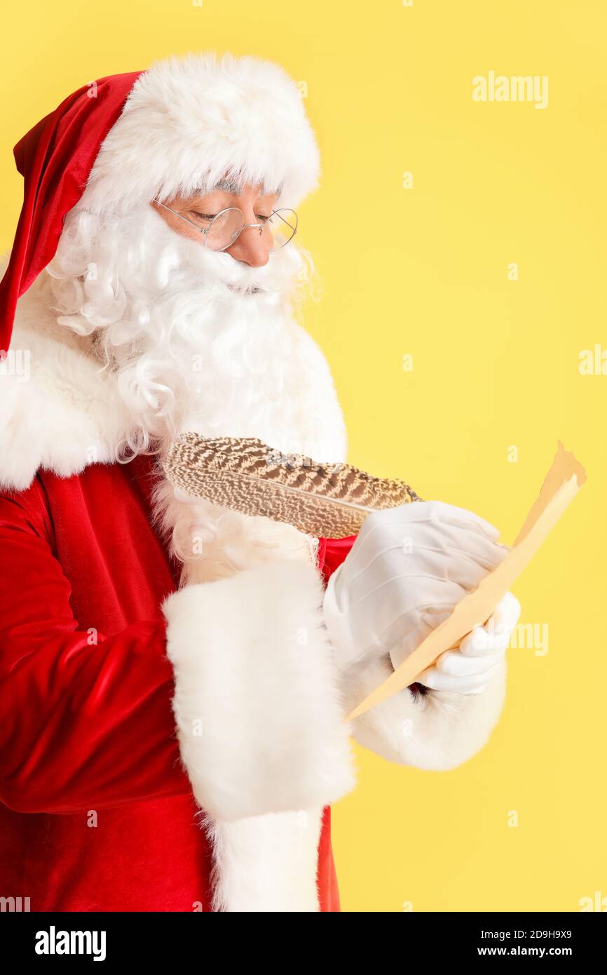 Santa Claus making list of gifts on color background Stock Photo - Alamy