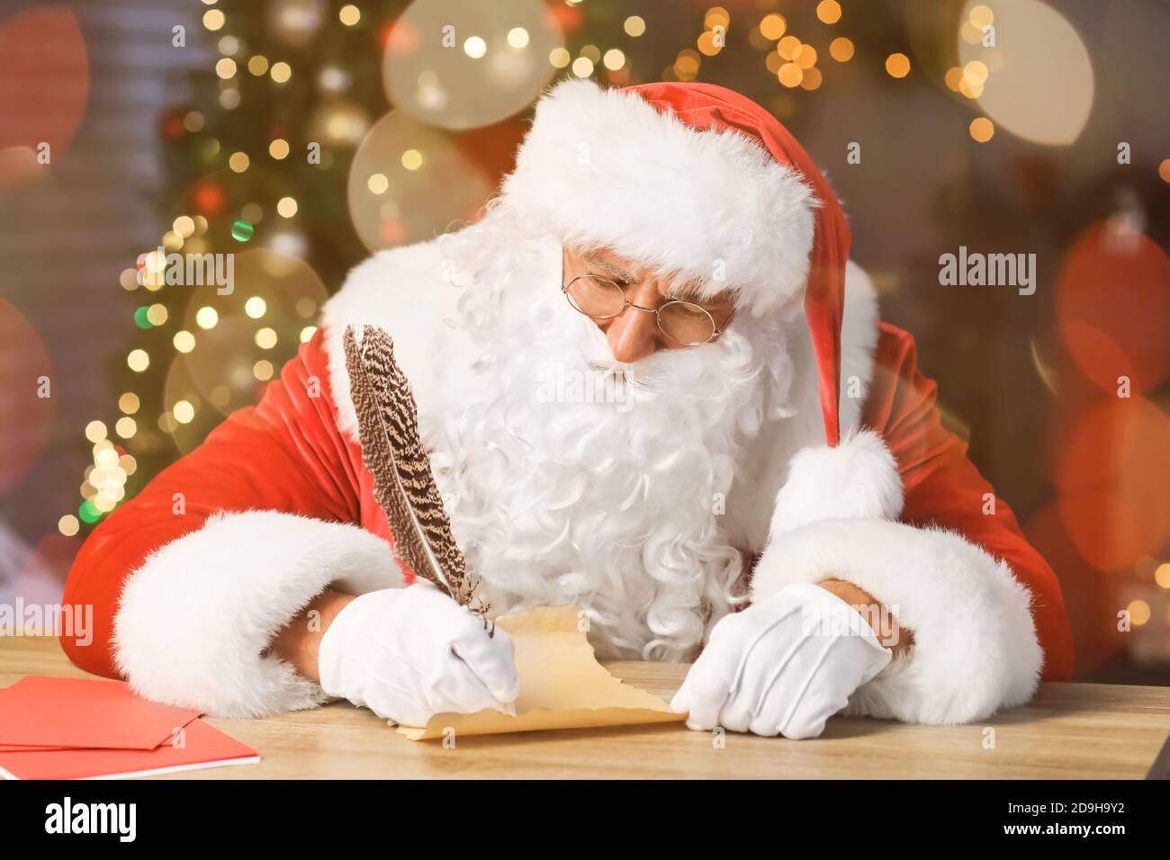 Santa Claus making list of gifts at table Stock Photo - Alamy