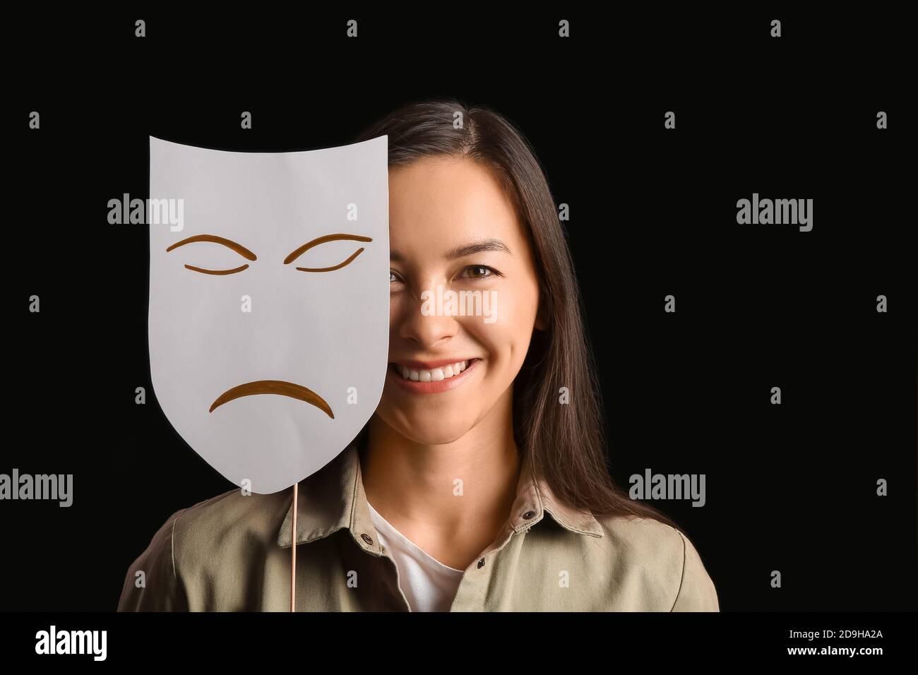 Happy actress with sad mask on dark background Stock Photo - Alamy