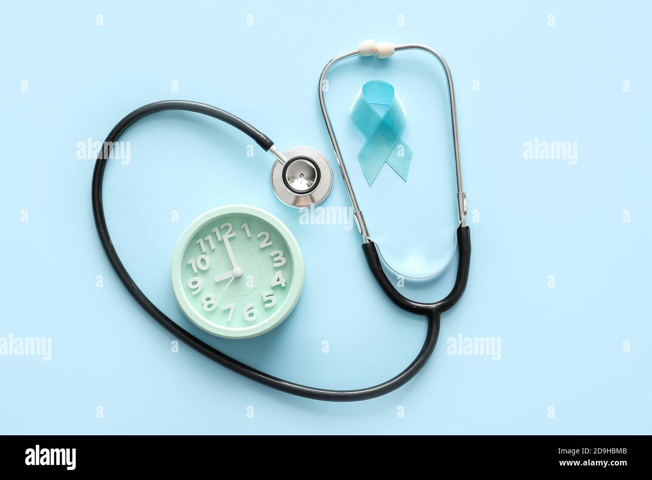 Blue ribbon, alarm clock and stethoscope on color background. Prostate ...