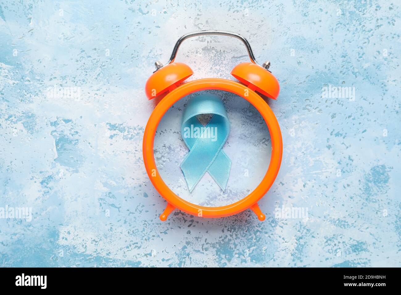 Blue ribbon and alarm clock on color background. Prostate cancer ...