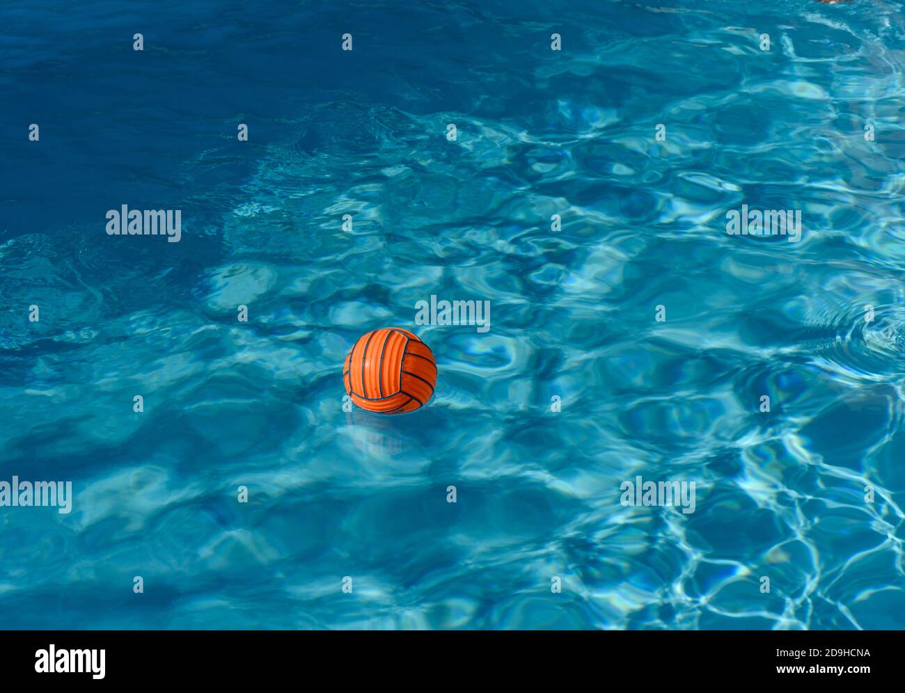 Orange volleyball floating on water in the swimming pool on a summer ...
