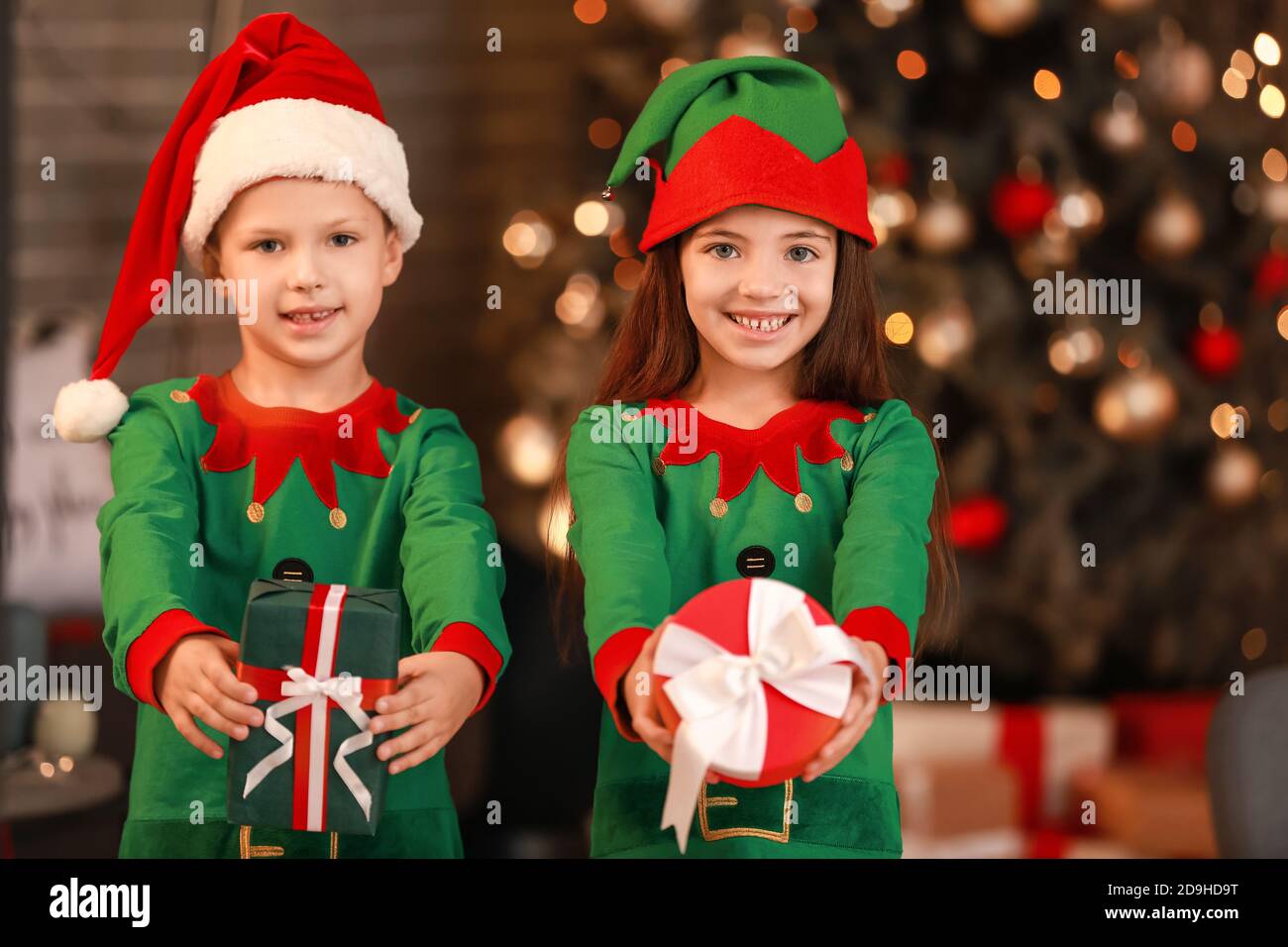 Cute little children in elves costumes and with gifts at home on ...