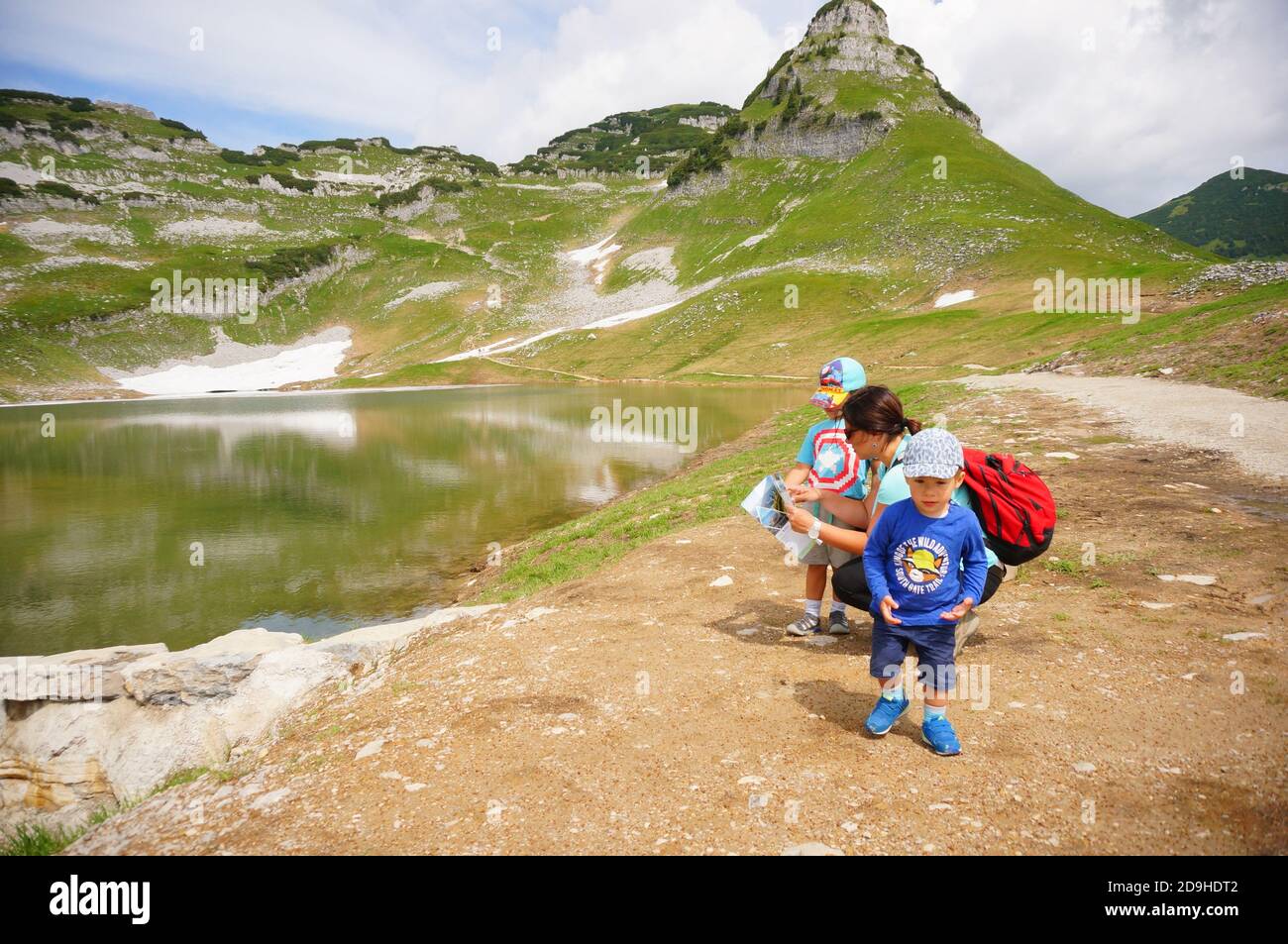 AUSSEERLAND, AUSTRIA - Jul 22, 2019: Woman reading a map next to kids ...