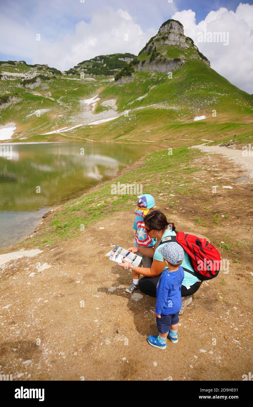 AUSSEERLAND, AUSTRIA - Jul 22, 2019: Woman reading a map next to kids ...