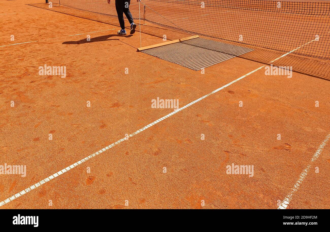 Male worker sweeping orange clay on an outdoor tennis court Stock Photo ...