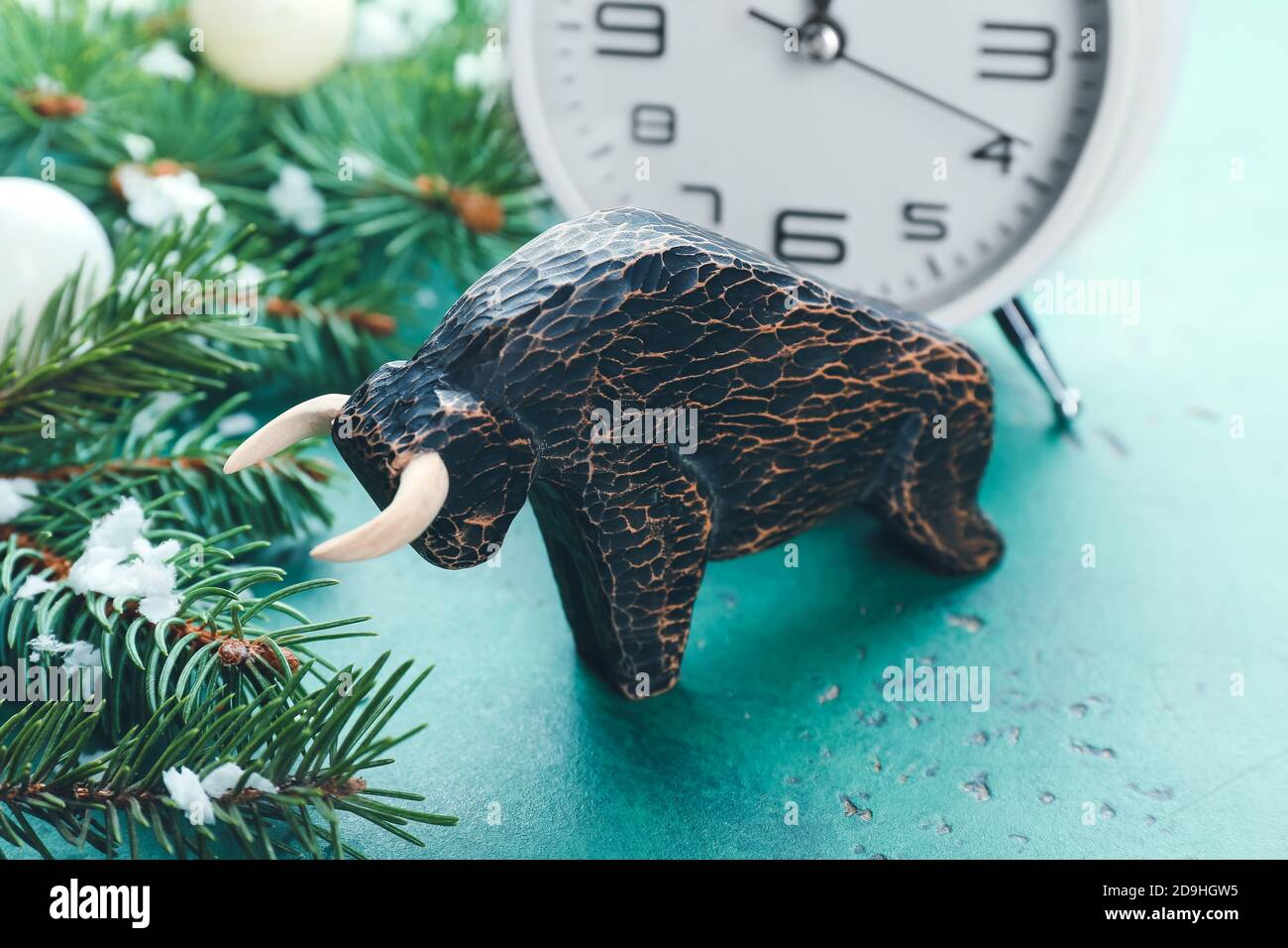 Figurine of bull, clock and New Year decor on color background Stock ...