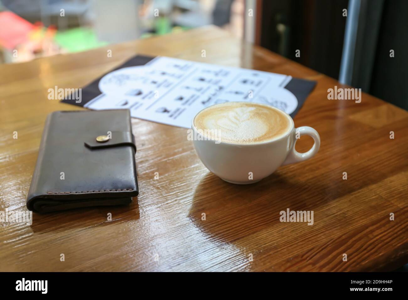 Cup of hot coffee, wallet and menu on table in cafe Stock Photo - Alamy