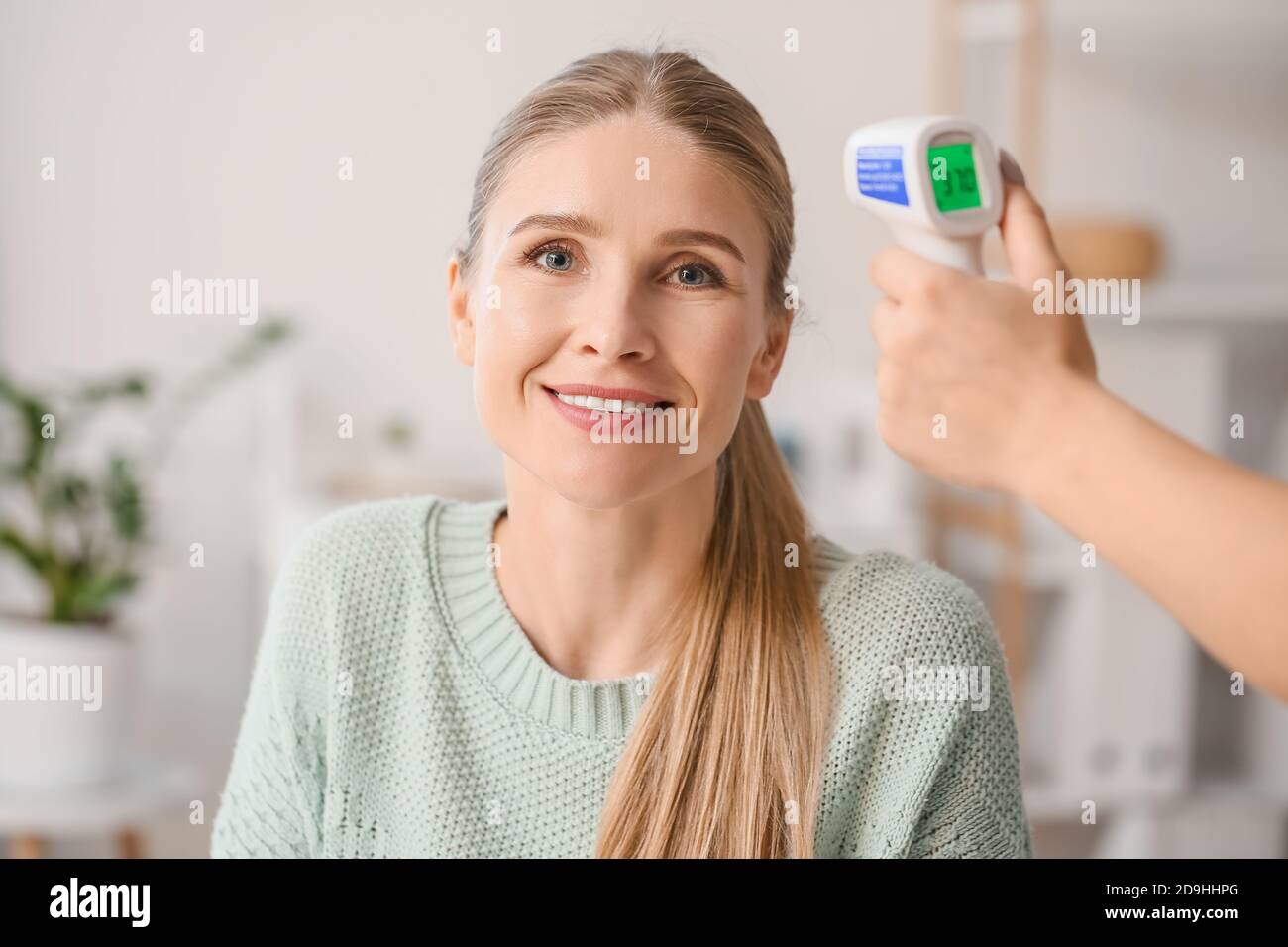 Measuring of woman's temperature in office. Coronavirus epidemic Stock ...