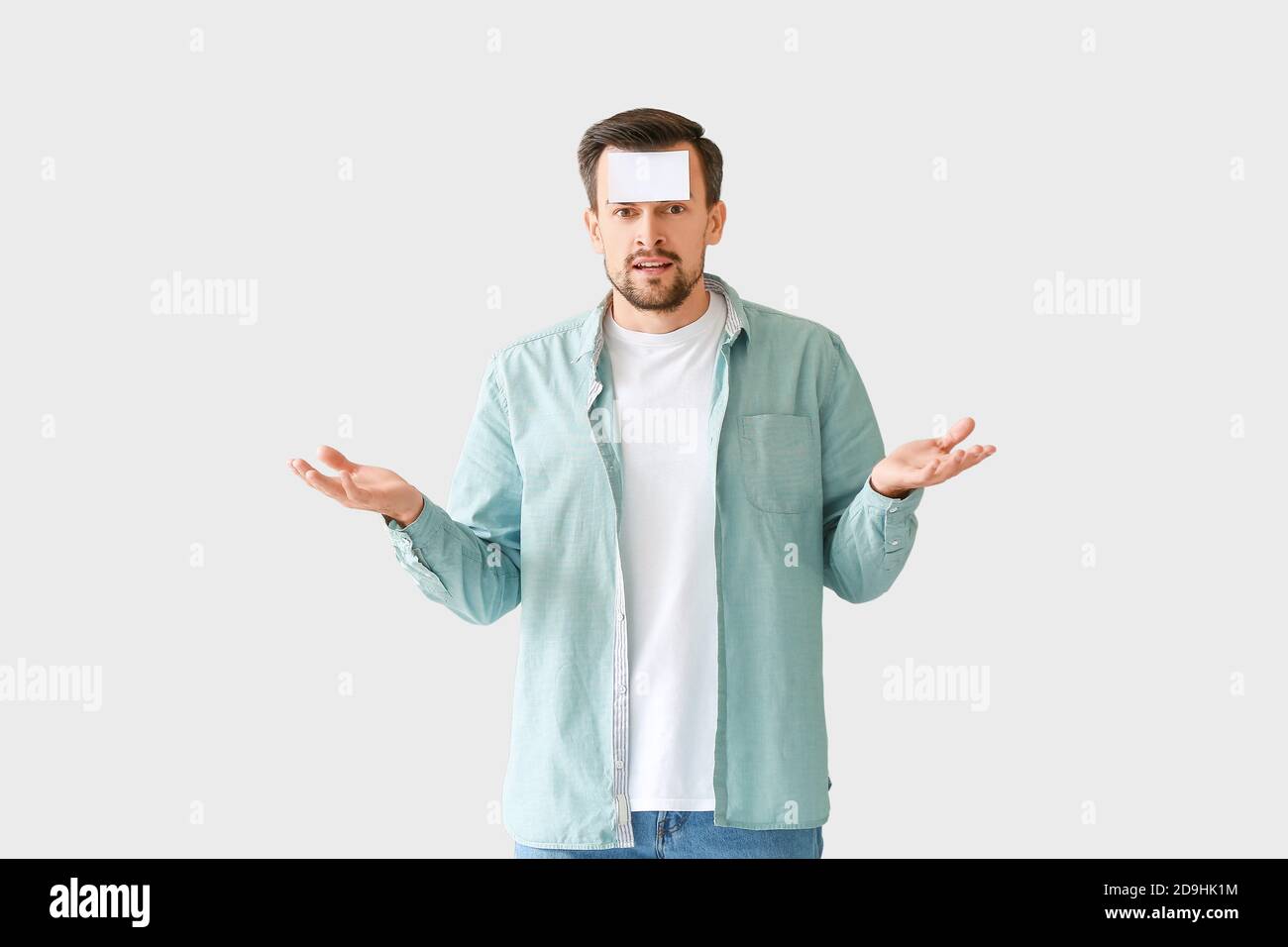 Confused man with blank note paper on his forehead against grey ...
