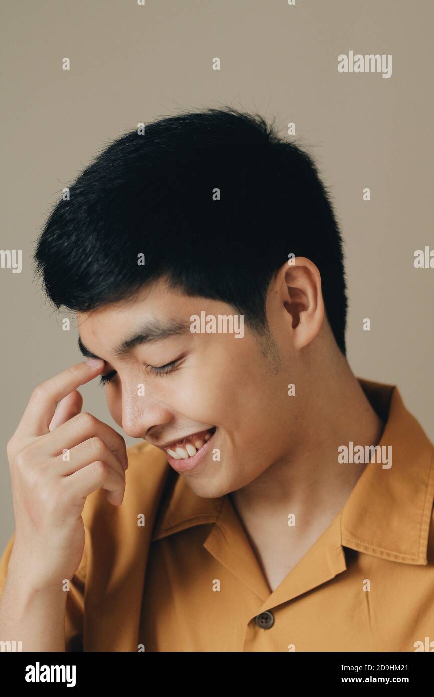 Closeup vertical portrait of a cute Asian man giggling embarrassedly ...