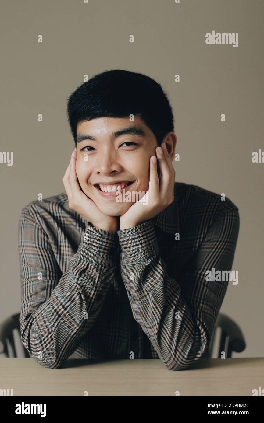 Closeup vertical portrait of a handsome smiling Asian man keeping hands ...