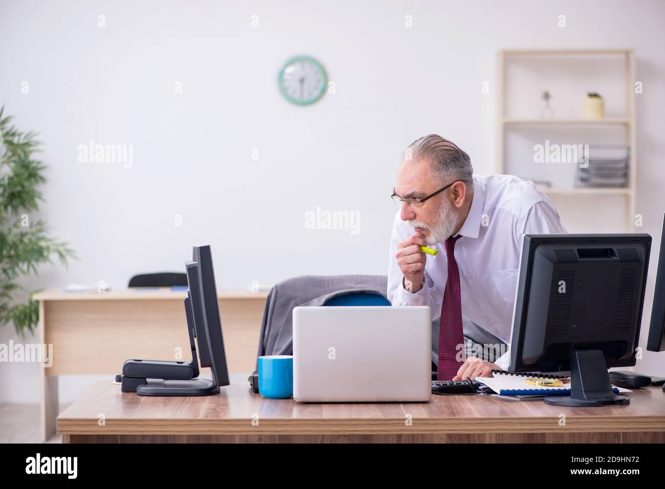 Old boss sitting at desktop in the office Stock Photo - Alamy