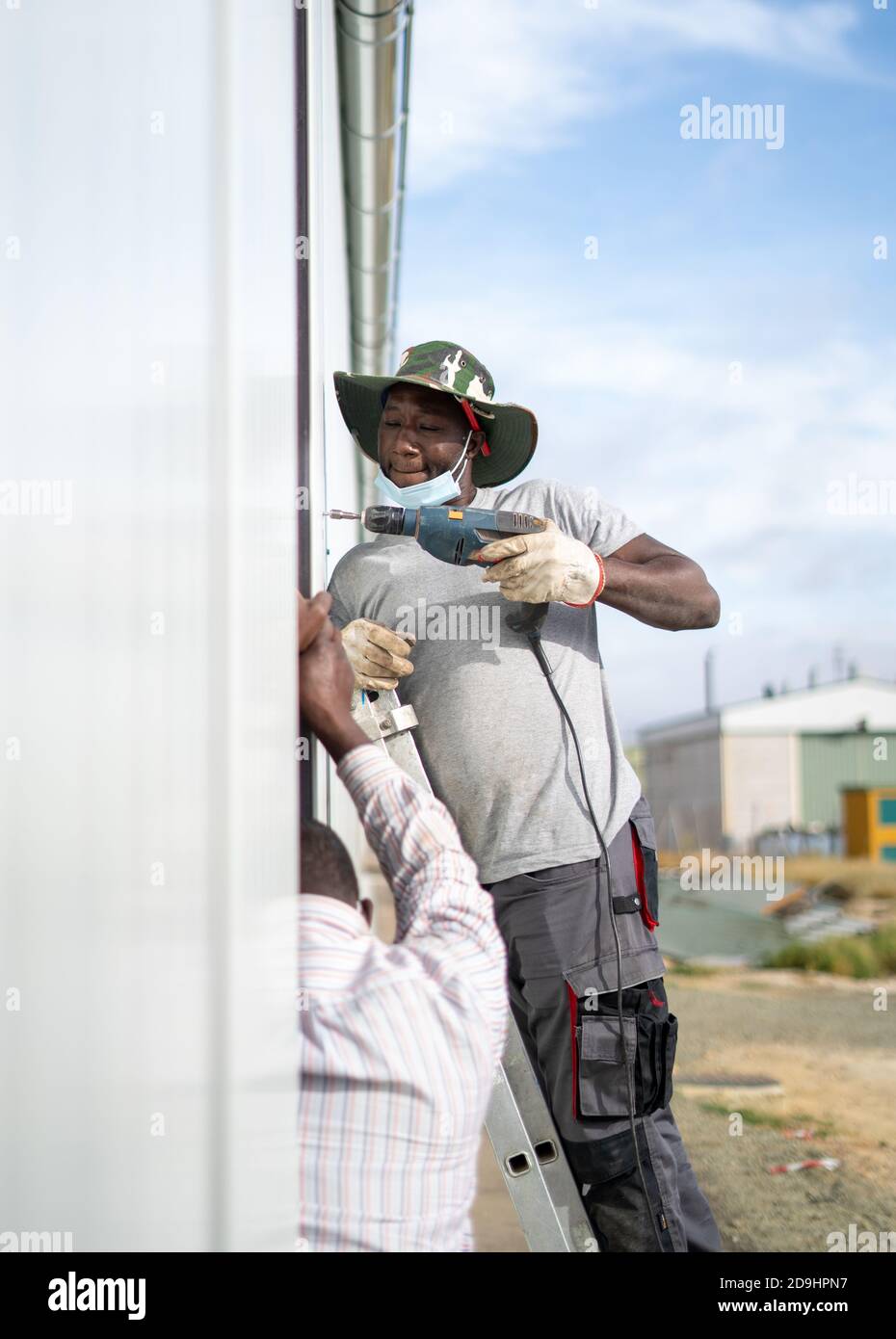 Afro-American craftsman drilling a wall with a drill machine Stock ...