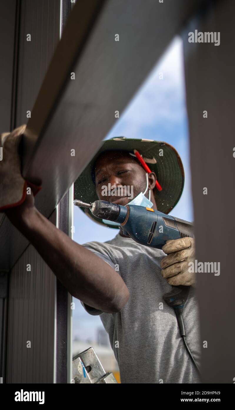 Afro-American craftsman drilling a wall with a drill machine Stock ...