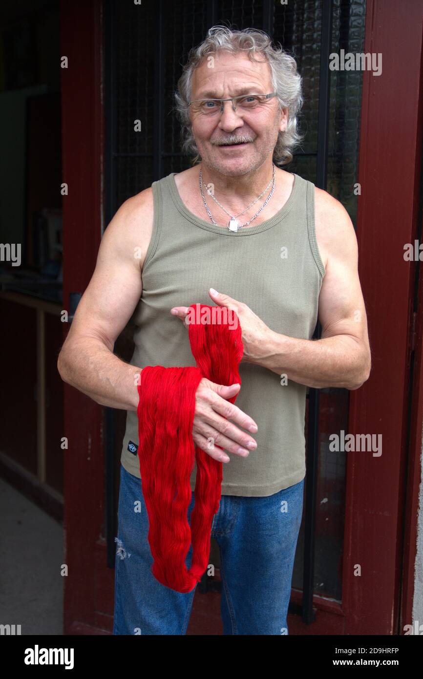 Thierry Roger, wool dyer, holds a skein of red wool that he has dyed at ...
