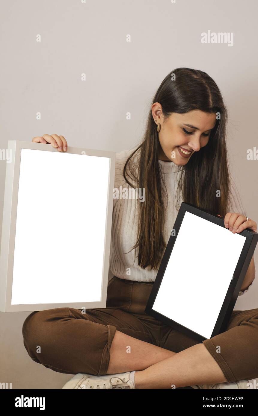 Vertical shot of a casual happy charming female holding two different ...