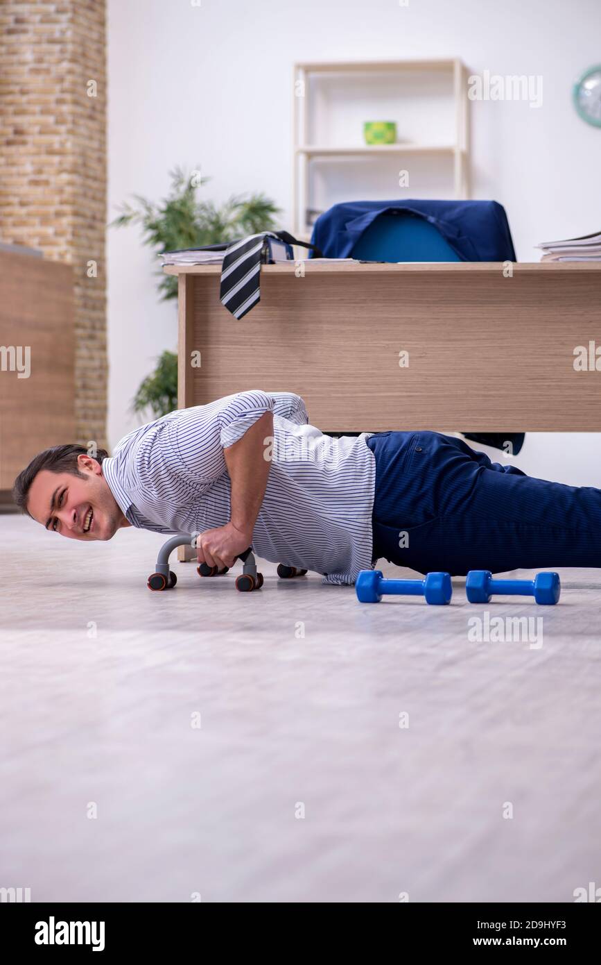 Handsome male employee doing exercises in the office Stock Photo - Alamy