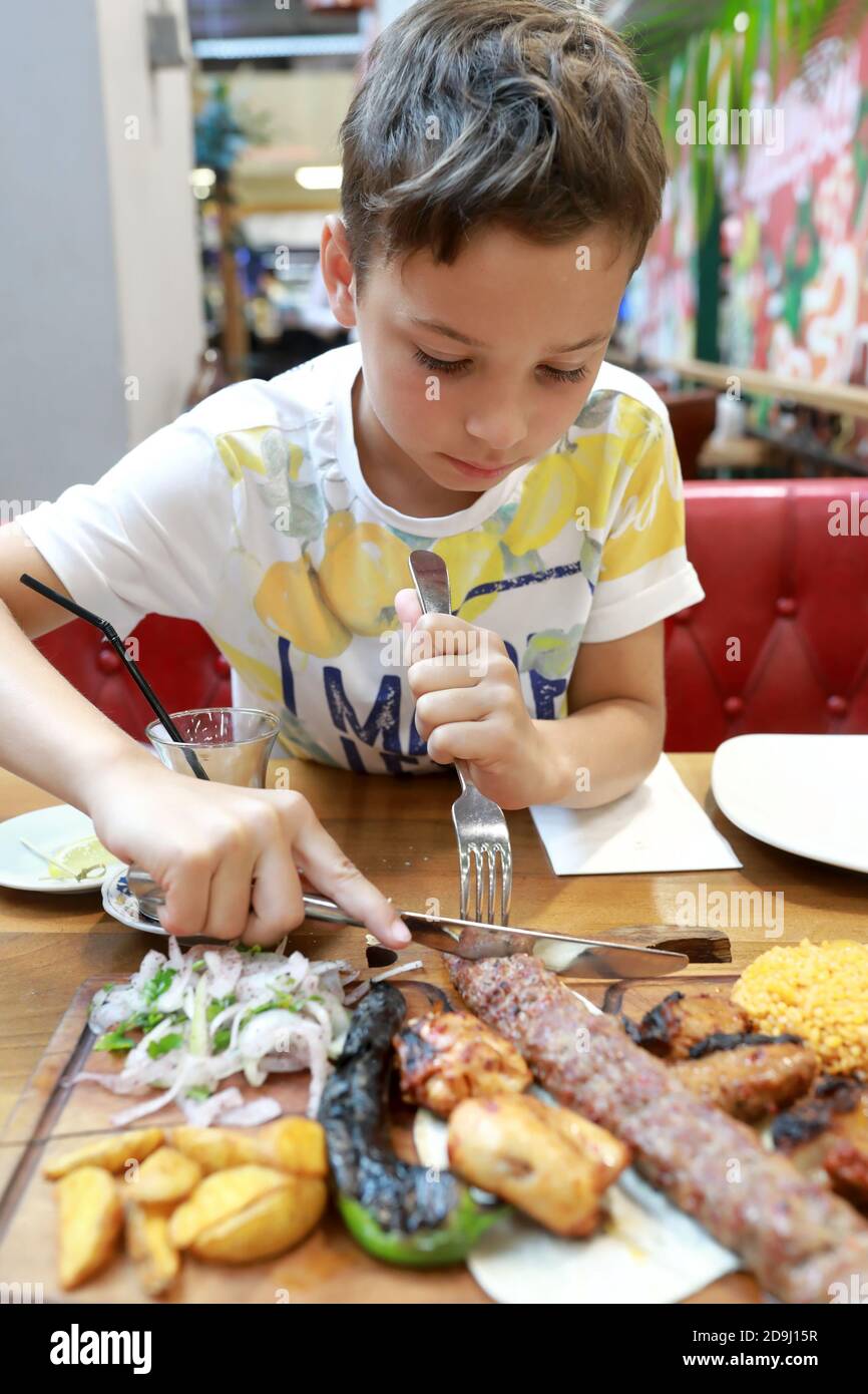 Child cutting kebabs on wooden board in Turkish restaurant Stock Photo ...