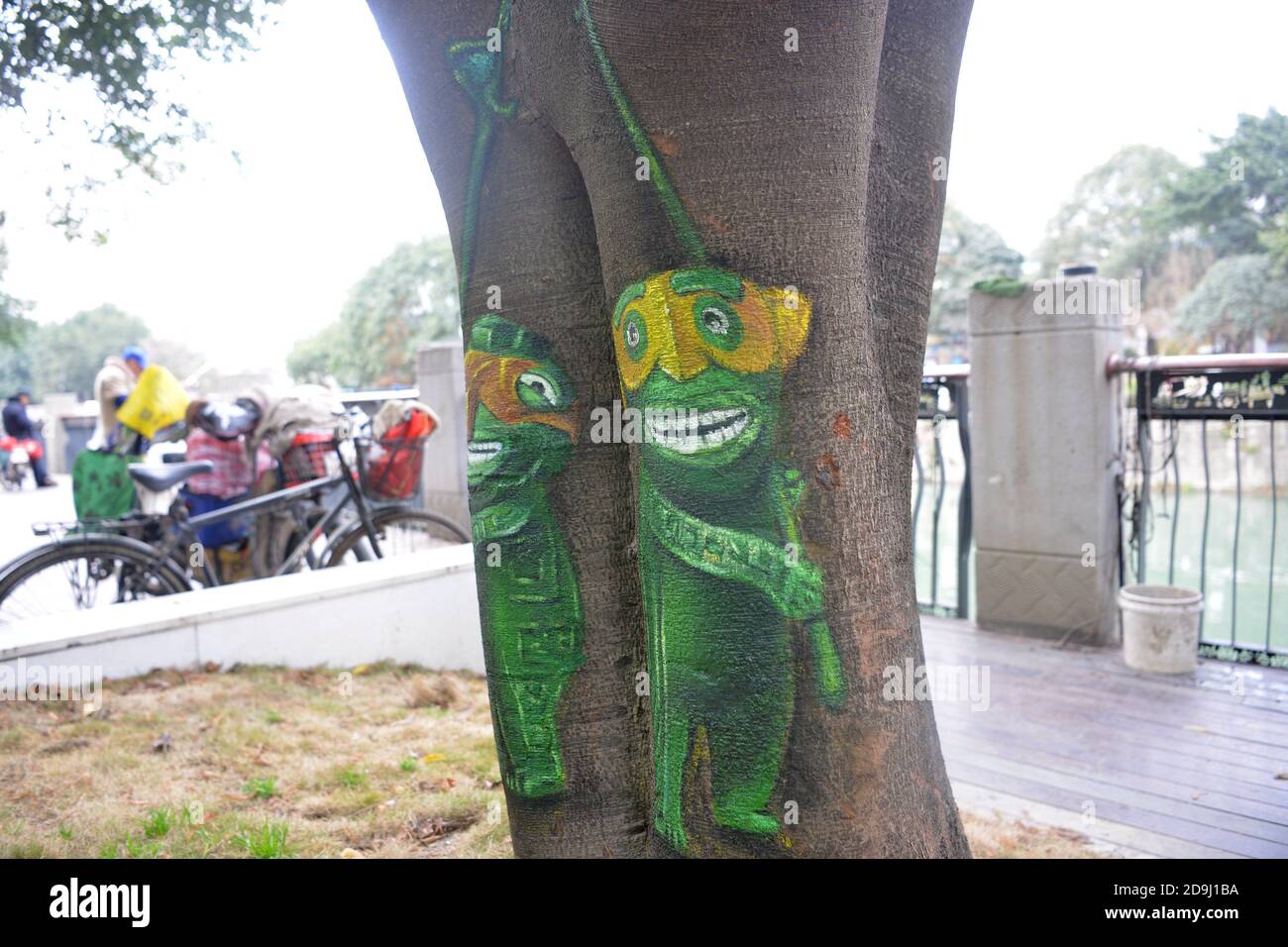 More than ten trees on a street are painted with graffiti, showing the ...