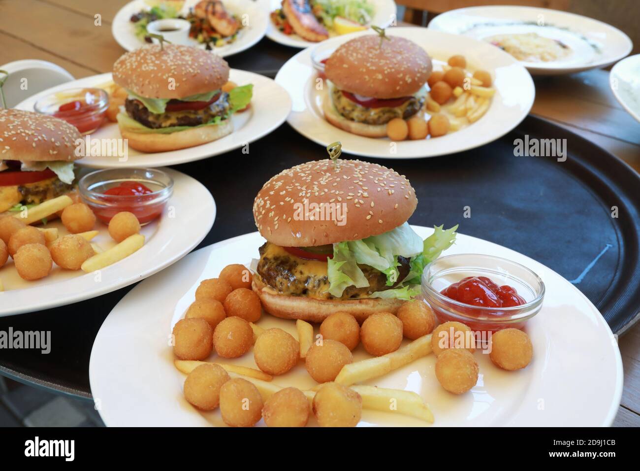 Plates with burgers and potatoes on tray in restaurant Stock Photo - Alamy