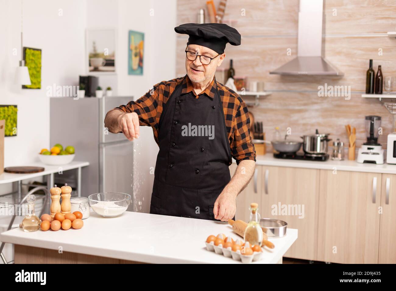 Experienced baker spreading flour in home kitchen for food preparation ...
