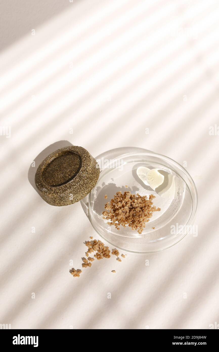 Solid bar of soap and clay powder on plate, striped shadow backround ...