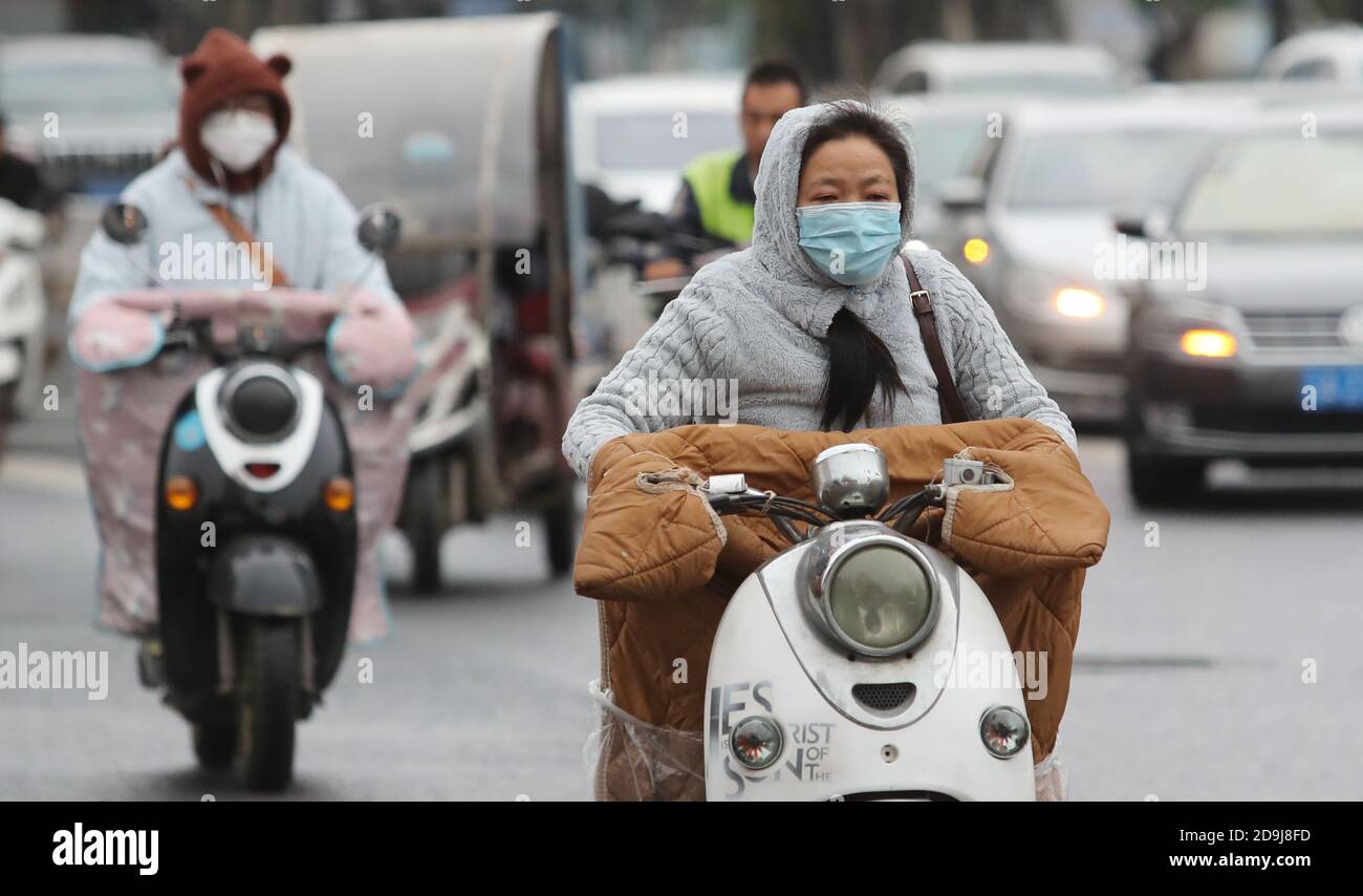 People wear thick clothes and hats while riding on the road because of ...