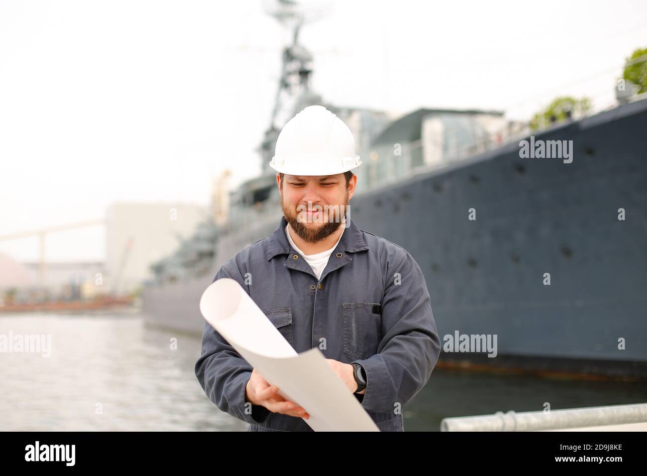 Maritime engineer looking at blueprints and standing near vessel Stock ...
