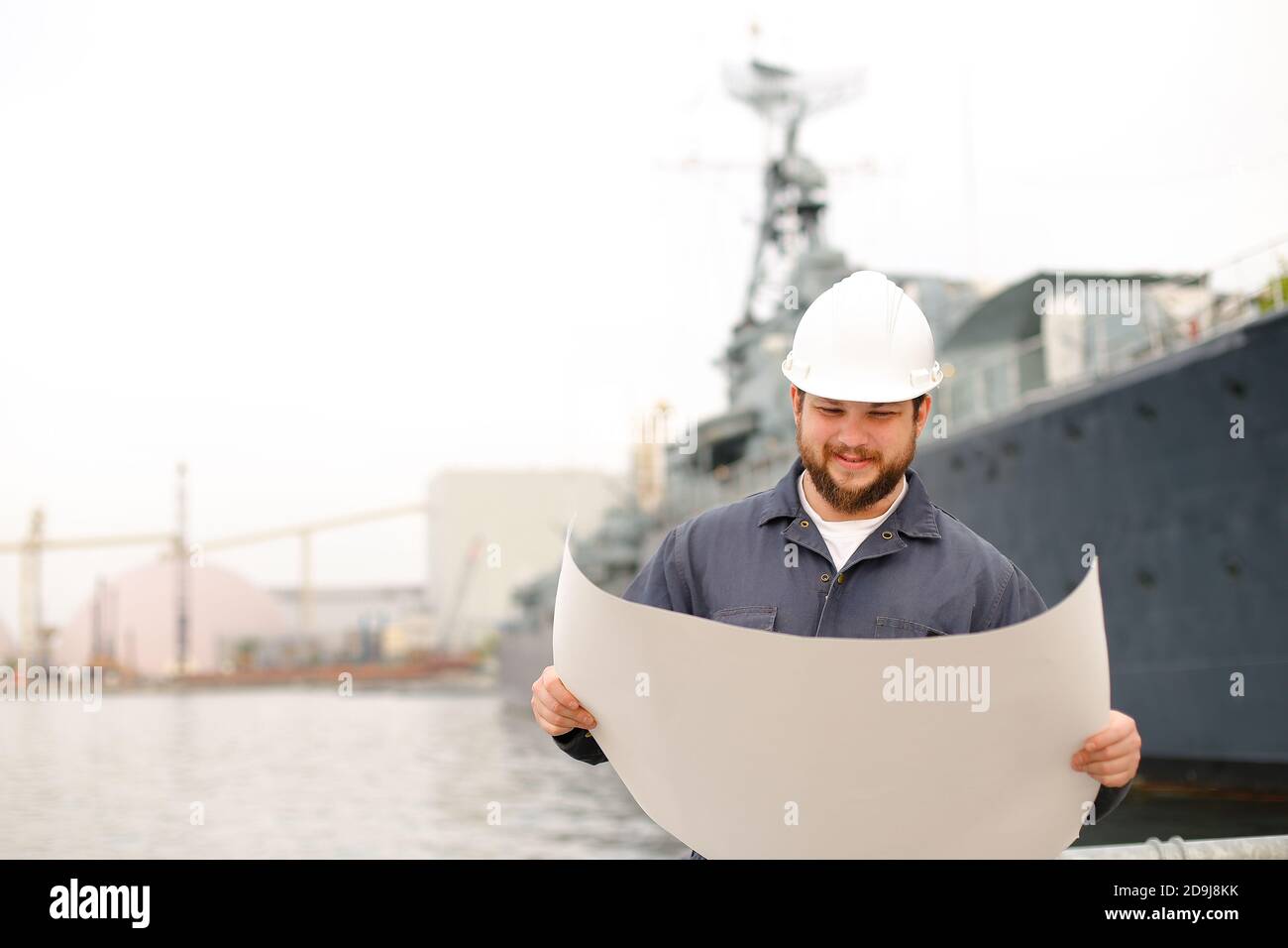 Maritime chief officer reading blueprints and standing near vessel ...